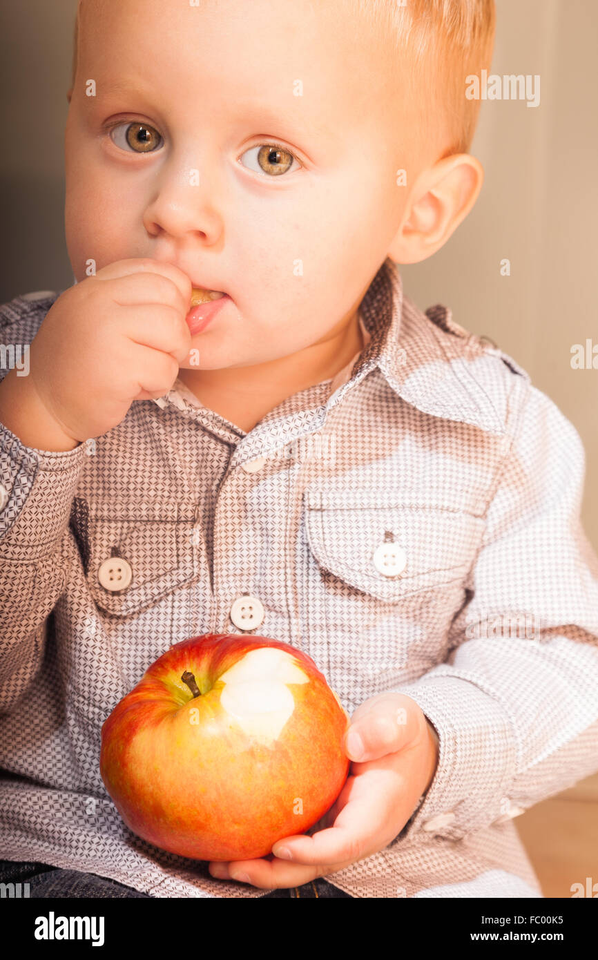 Little boy child kid eating apple fruit at home Stock Photo - Alamy