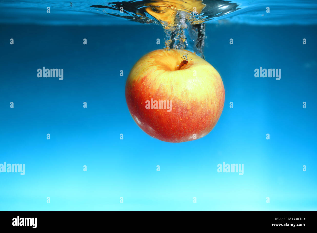Yellow apple in the water splash over blue Stock Photo - Alamy