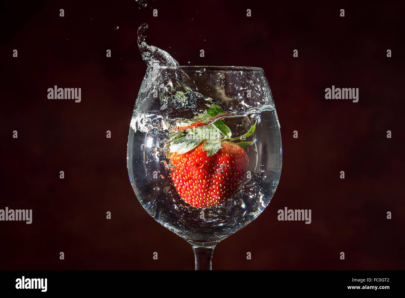 fresh strawberry drop in water, contain in wine glass, splashing Stock ...