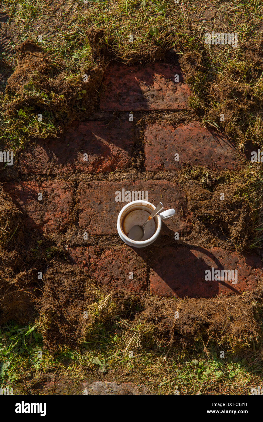 A cup on a brick wall underneath a meadow Stock Photo - Alamy