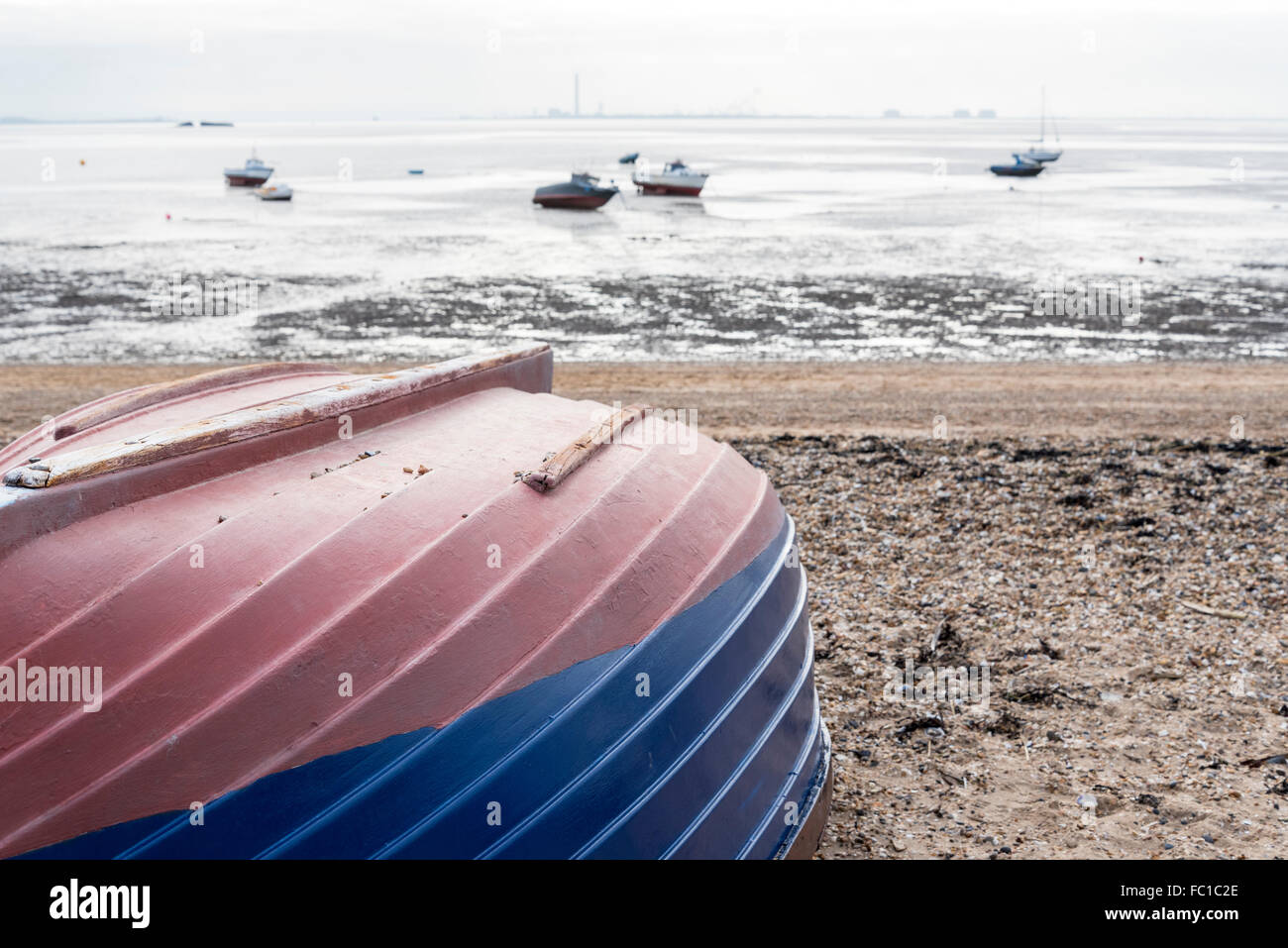 An upside down red and blue clinker built boat on the beach at ...