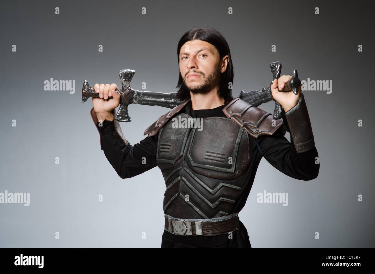 Angry knight with sword against dark background Stock Photo - Alamy