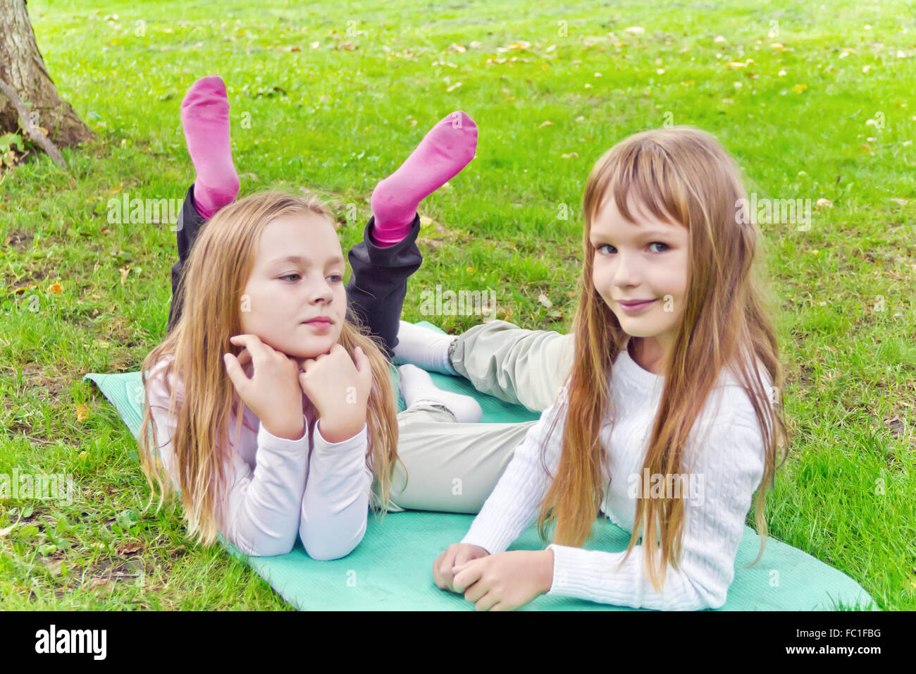 Two girls sitting on grass Stock Photo - Alamy