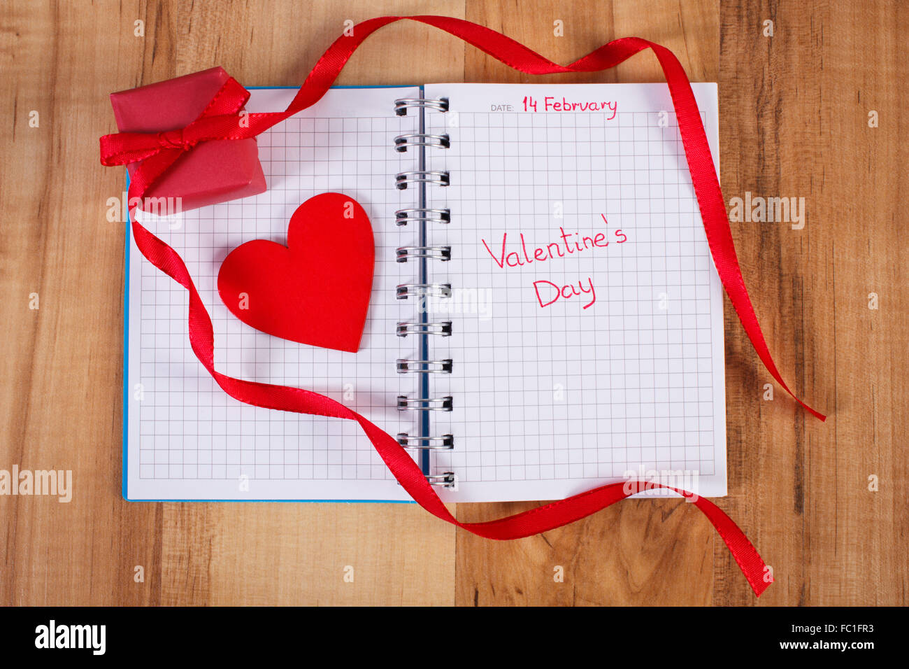 Date of February 14 written in notebook or calendar, wrapped gift with ...