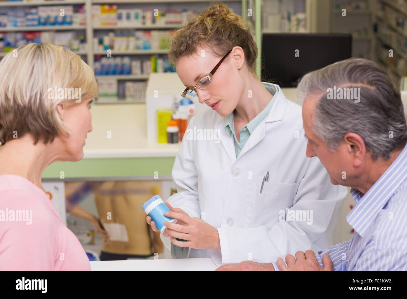 Pharmacist holding a bottle of drugs talking to customer Stock Photo ...