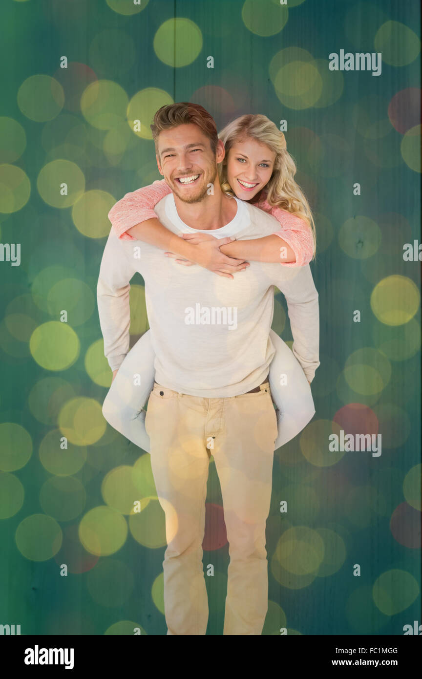Composite image of handsome man giving piggy back to his girlfriend ...