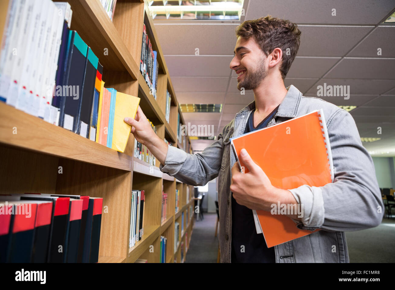 Student picking a book from shelf in library Stock Photo - Alamy
