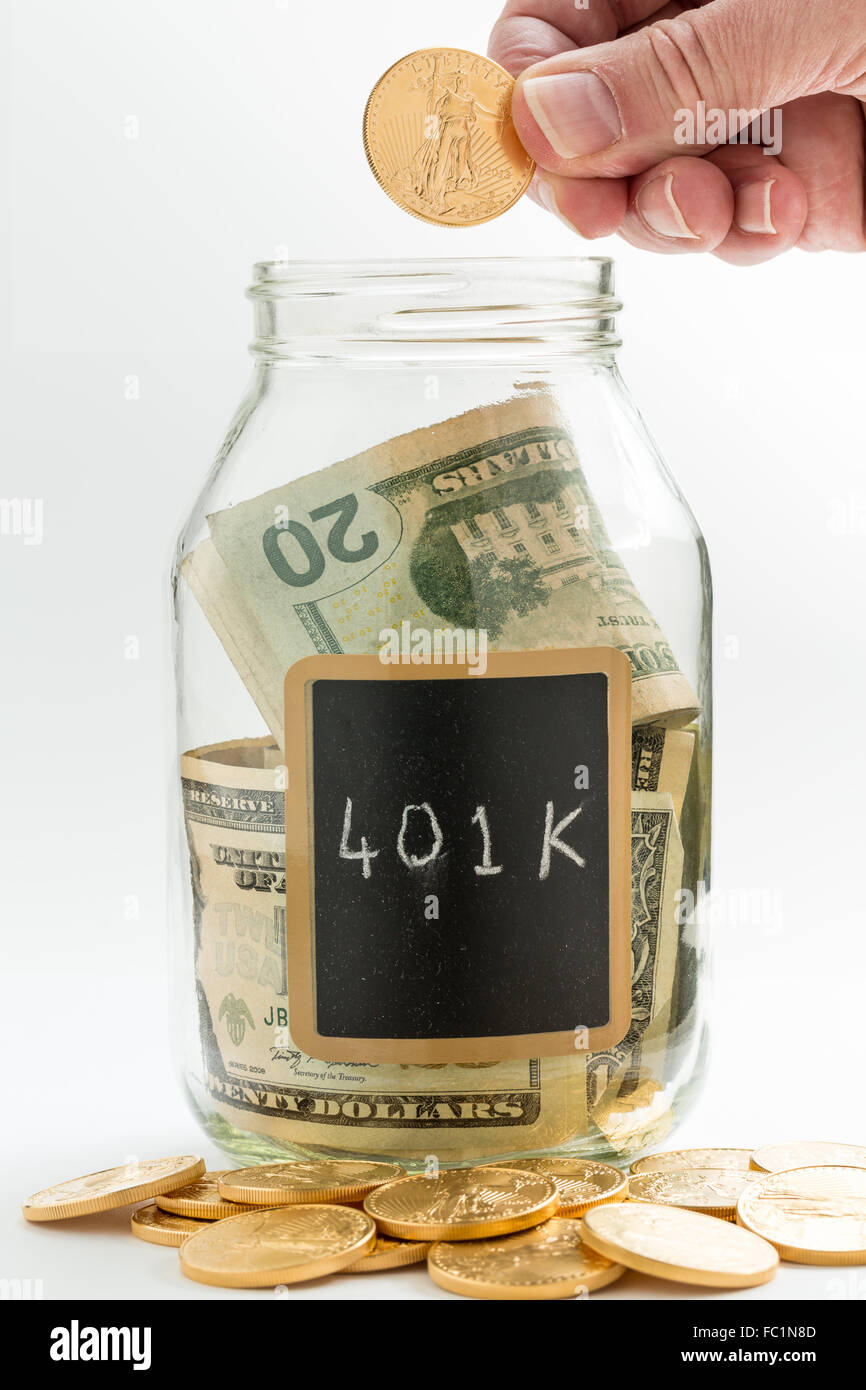 Hand inserting gold coin into saving jar Stock Photo - Alamy