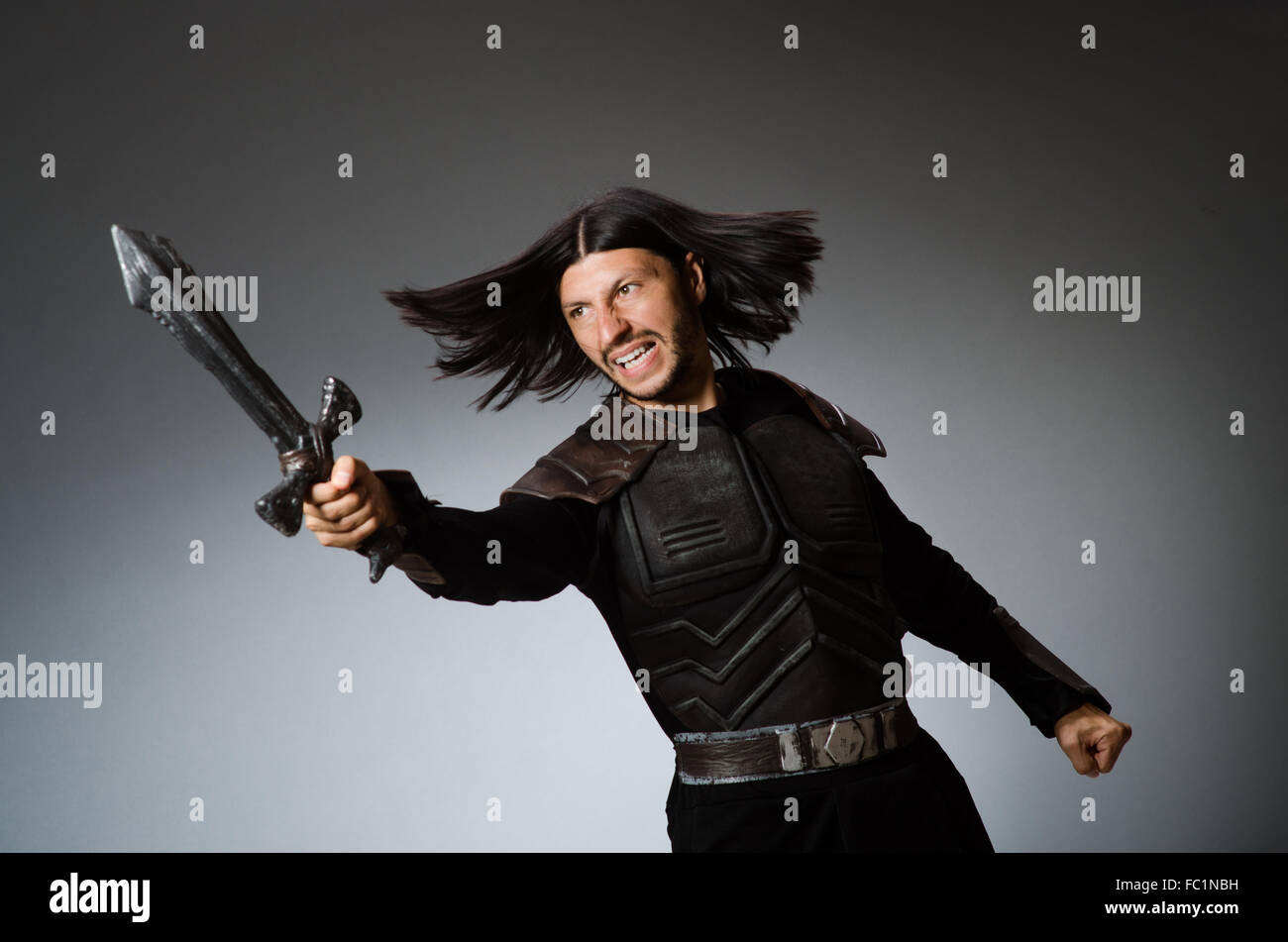 Angry knight with sword against dark background Stock Photo - Alamy