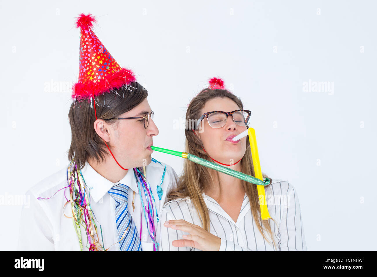 Geeky hipster wearing a party hat with blowing party horn Stock Photo ...