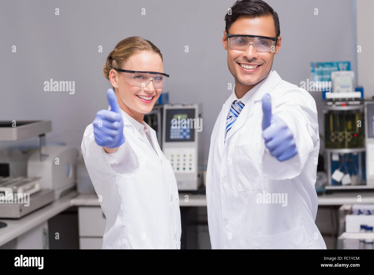 Smiling scientists looking at camera thumbs up Stock Photo - Alamy