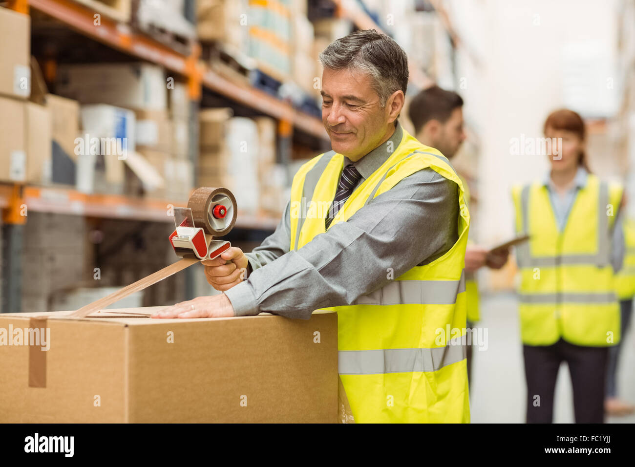 Warehouse worker sealing cardboard boxes for shipping Stock Photo - Alamy