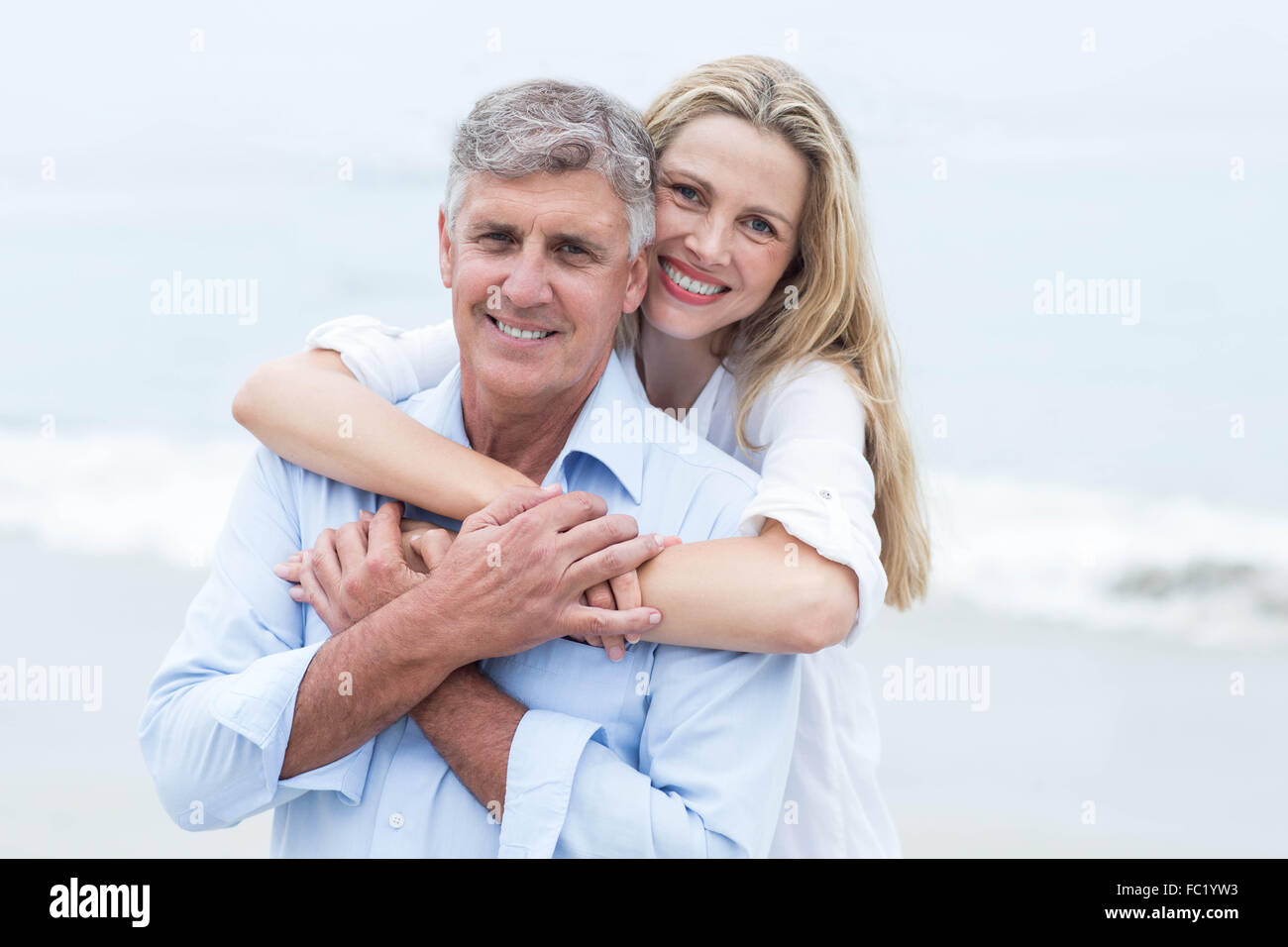 Happy couple hugging each other and looking at camera Stock Photo - Alamy