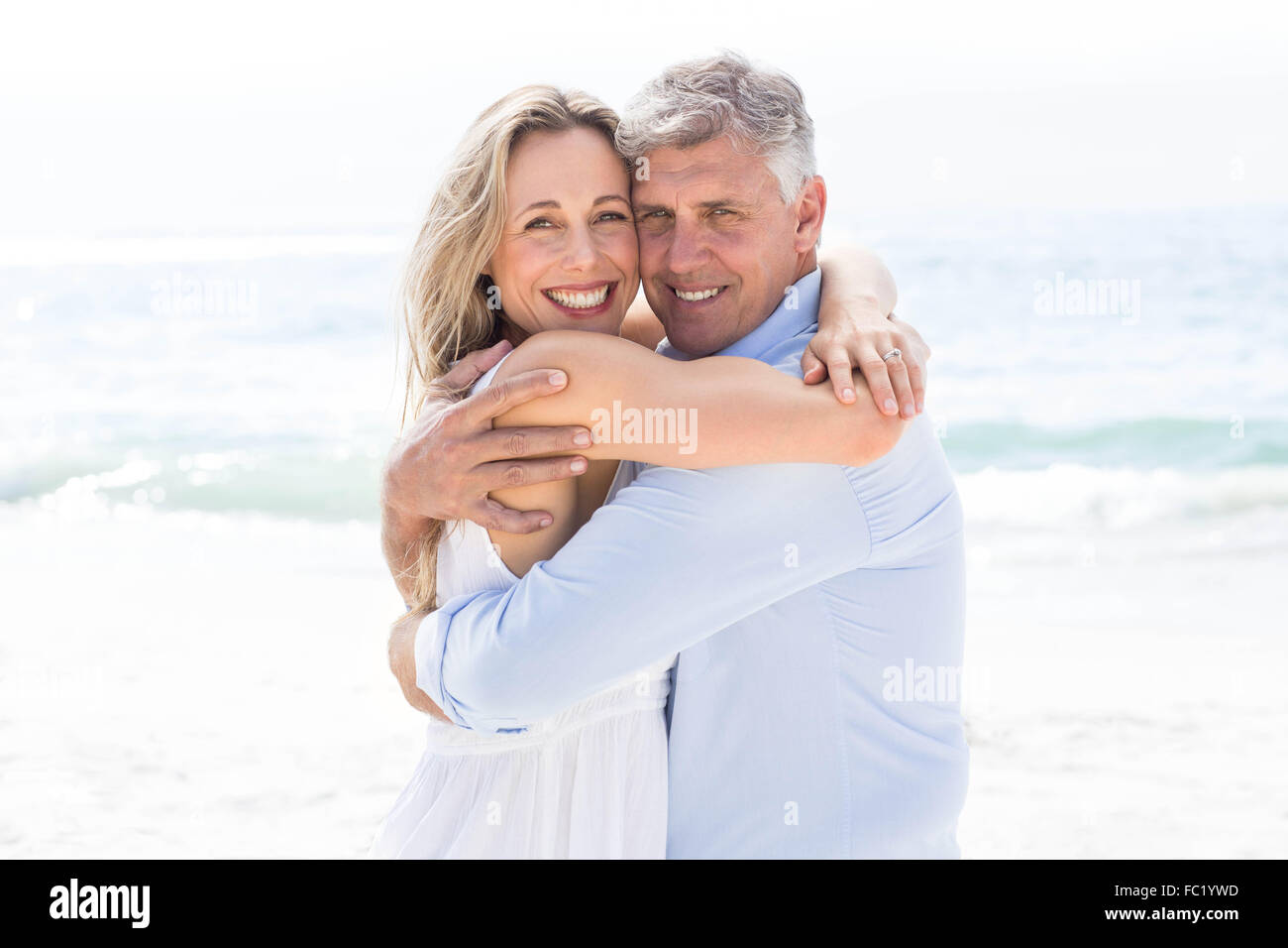 Happy couple hugging each other and looking at camera Stock Photo - Alamy