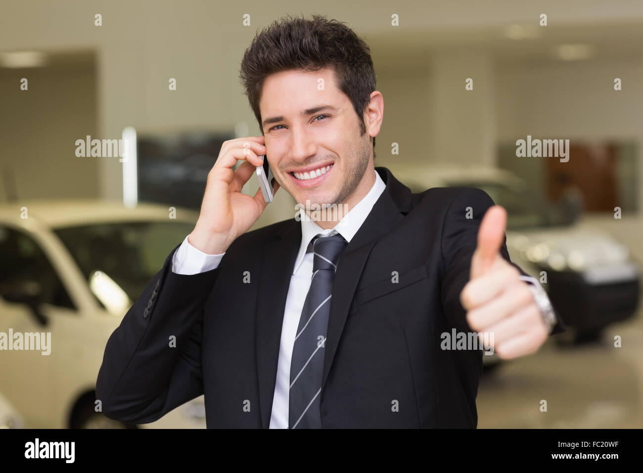 Smiling businessman giving thumbs up on phone Stock Photo - Alamy