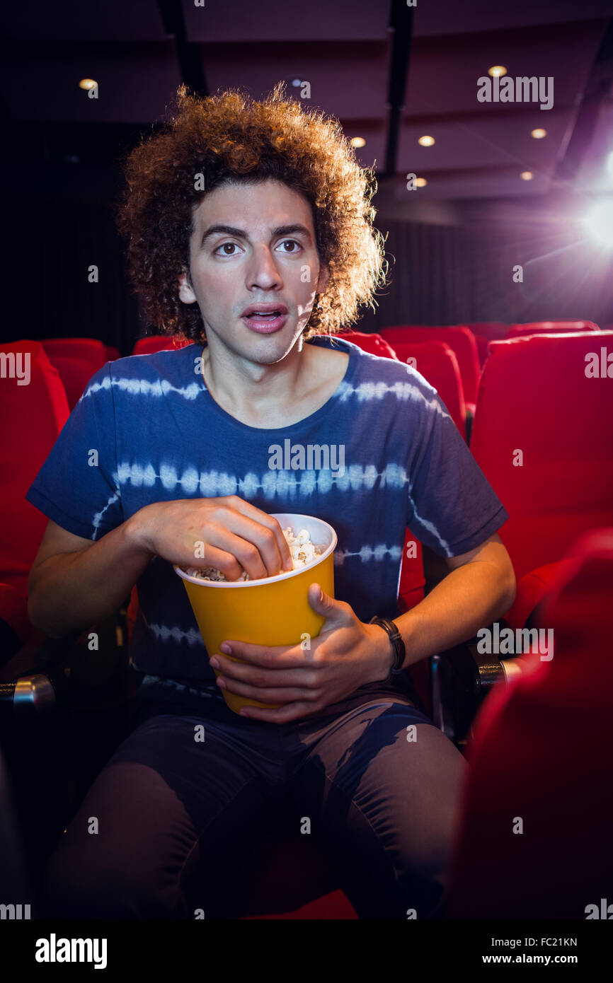 Young man watching a film and eating pop corn Stock Photo - Alamy