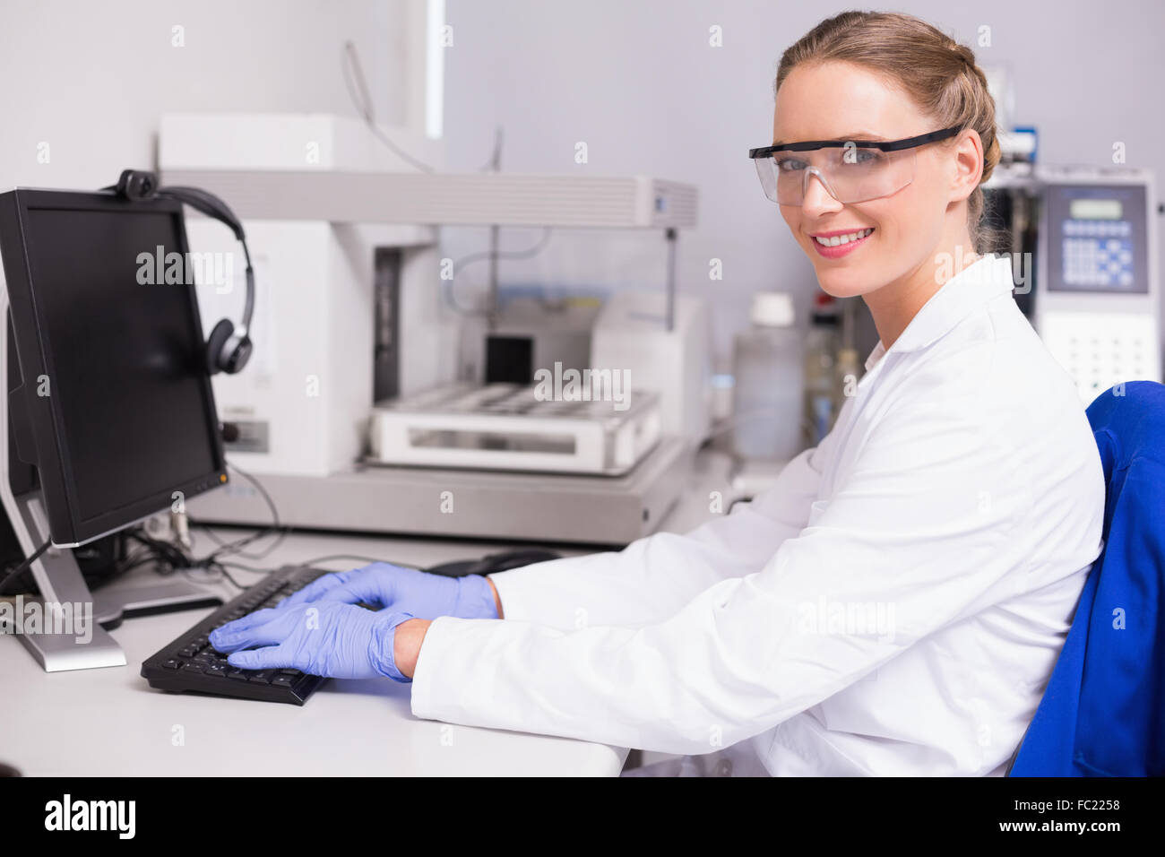 Smiling scientist looking at camera and using computer Stock Photo - Alamy