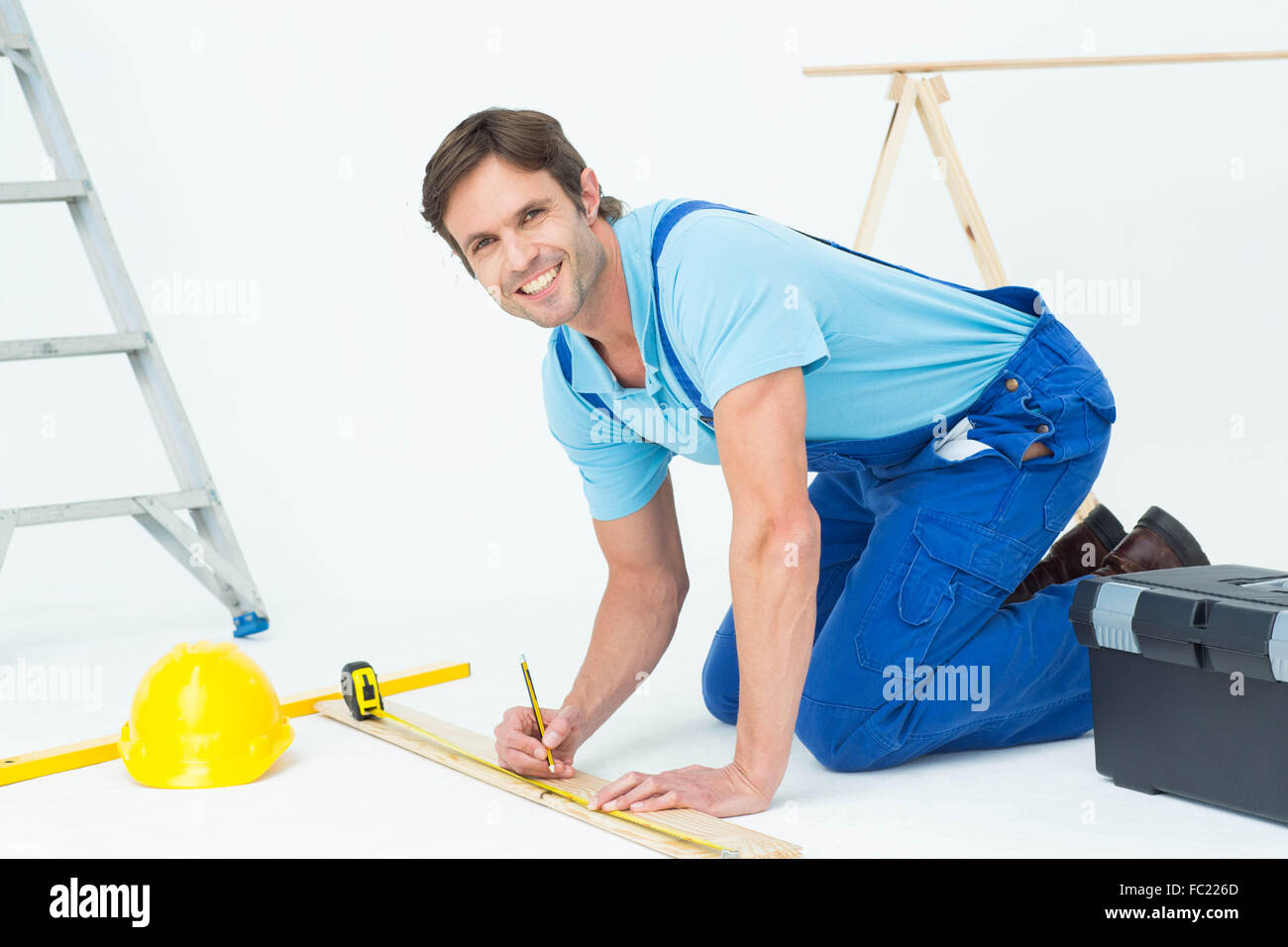 Confident worker marking on wood while measuring Stock Photo - Alamy