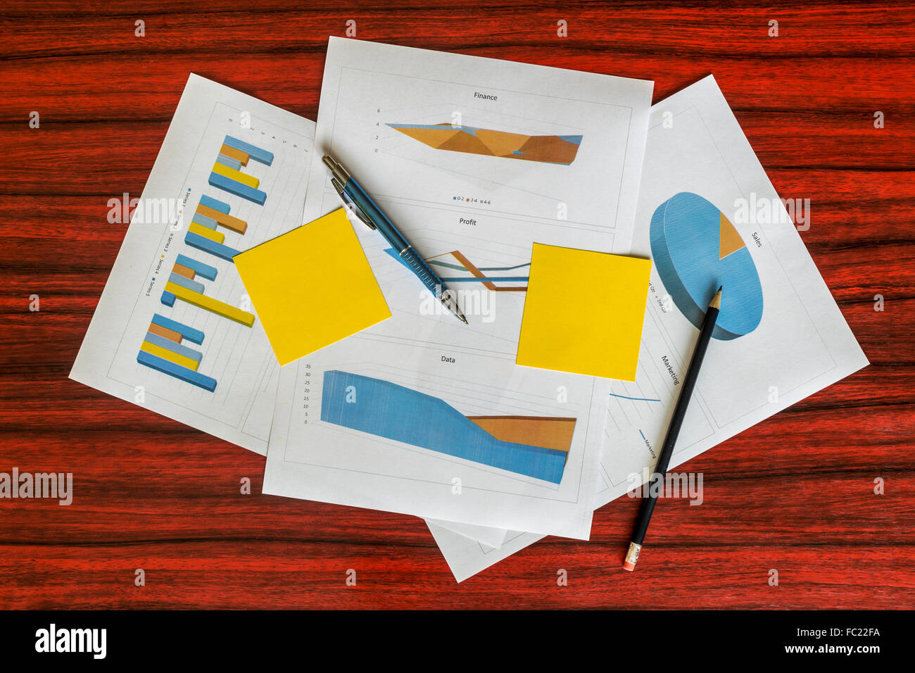 Bunch of printed charts and graphs with yellow notes, paper clips and ...