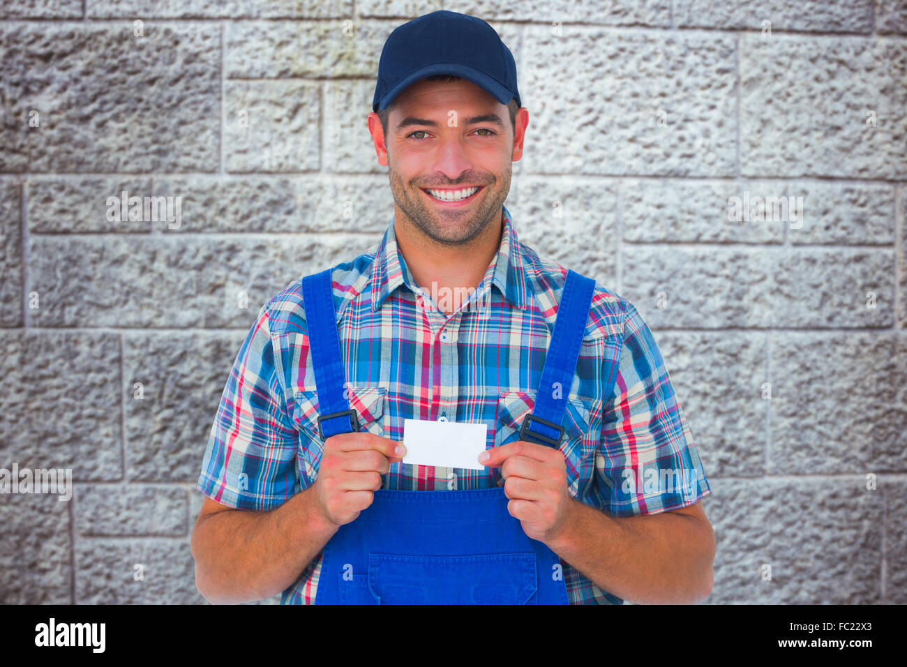 Composite image of portrait of happy handyman holding visiting card ...