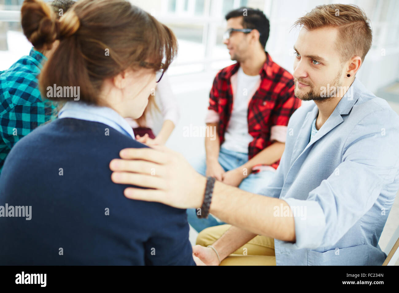 Young man reassuring his groupmate at psychological course Stock Photo ...