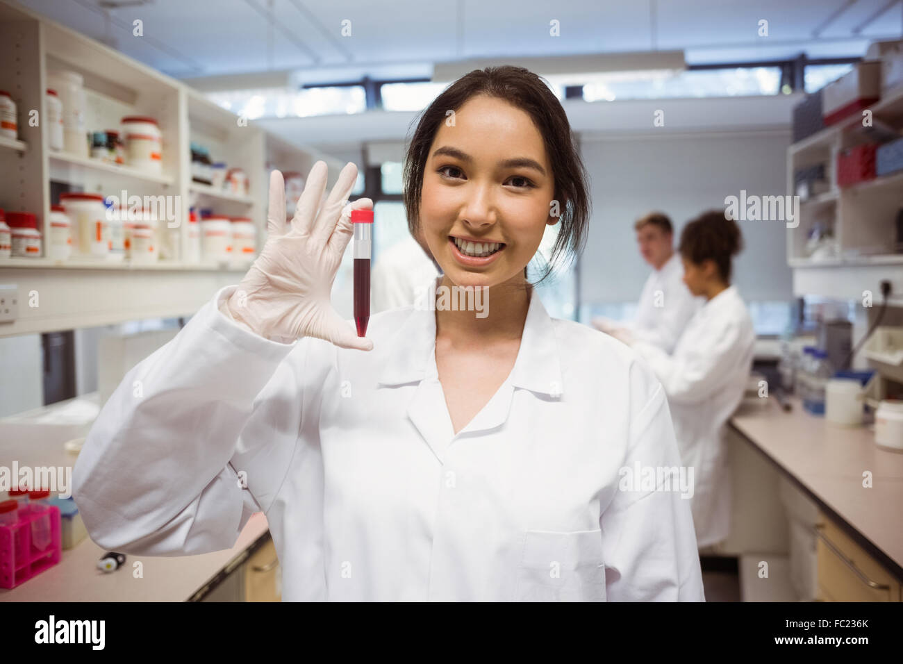 Pretty science student smiling and showing vial Stock Photo - Alamy