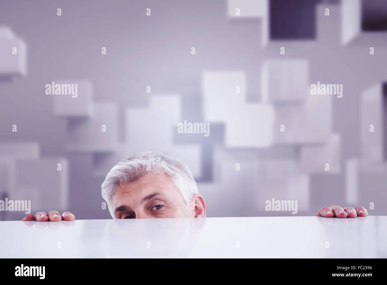 Composite image of businessman peeking over desk Stock Photo - Alamy