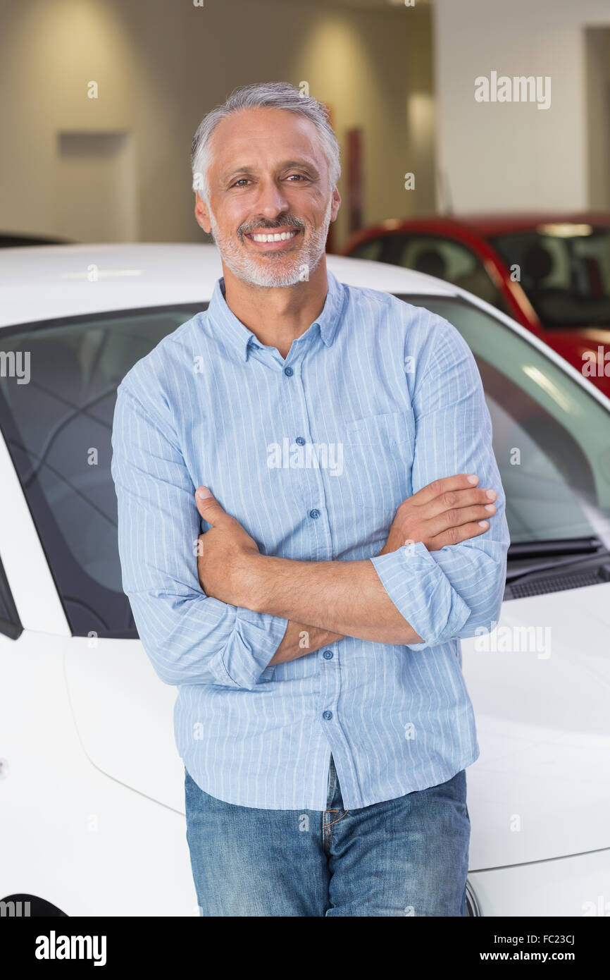 Smiling customer leaning on car with arms crossed Stock Photo - Alamy