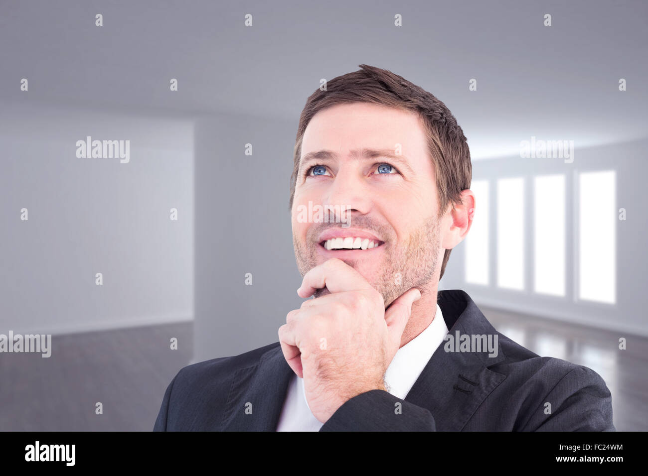 Composite image of businessman smiling and thinking Stock Photo - Alamy