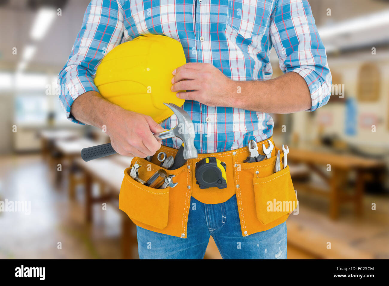Composite image of manual worker wearing tool belt while holding hammer ...
