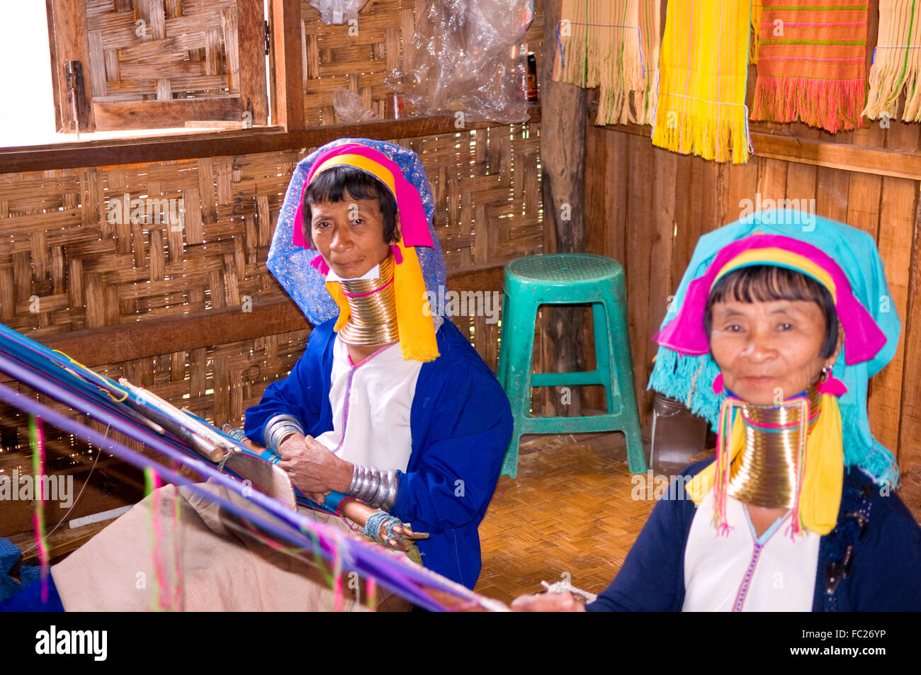 Women, weaving, wearing their traditional head scarf and neck rings ...