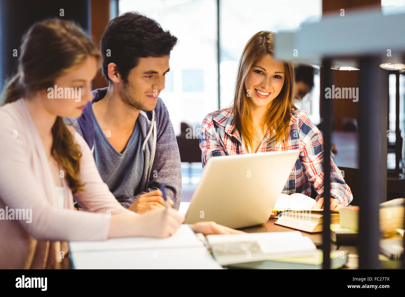 Student looking at camera while studying with classmates Stock Photo ...