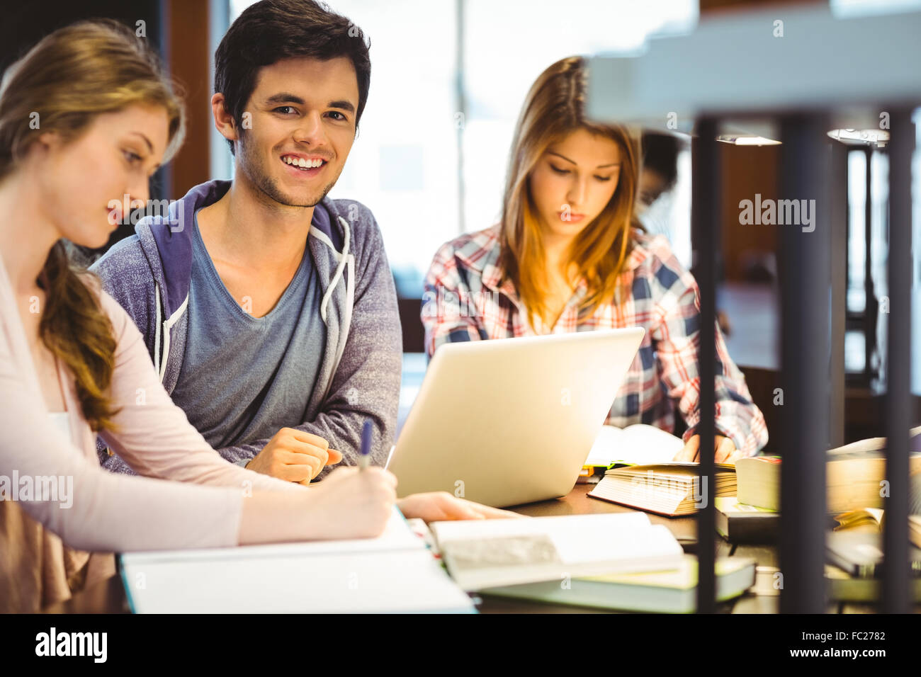 Student looking at camera while studying with classmates Stock Photo ...
