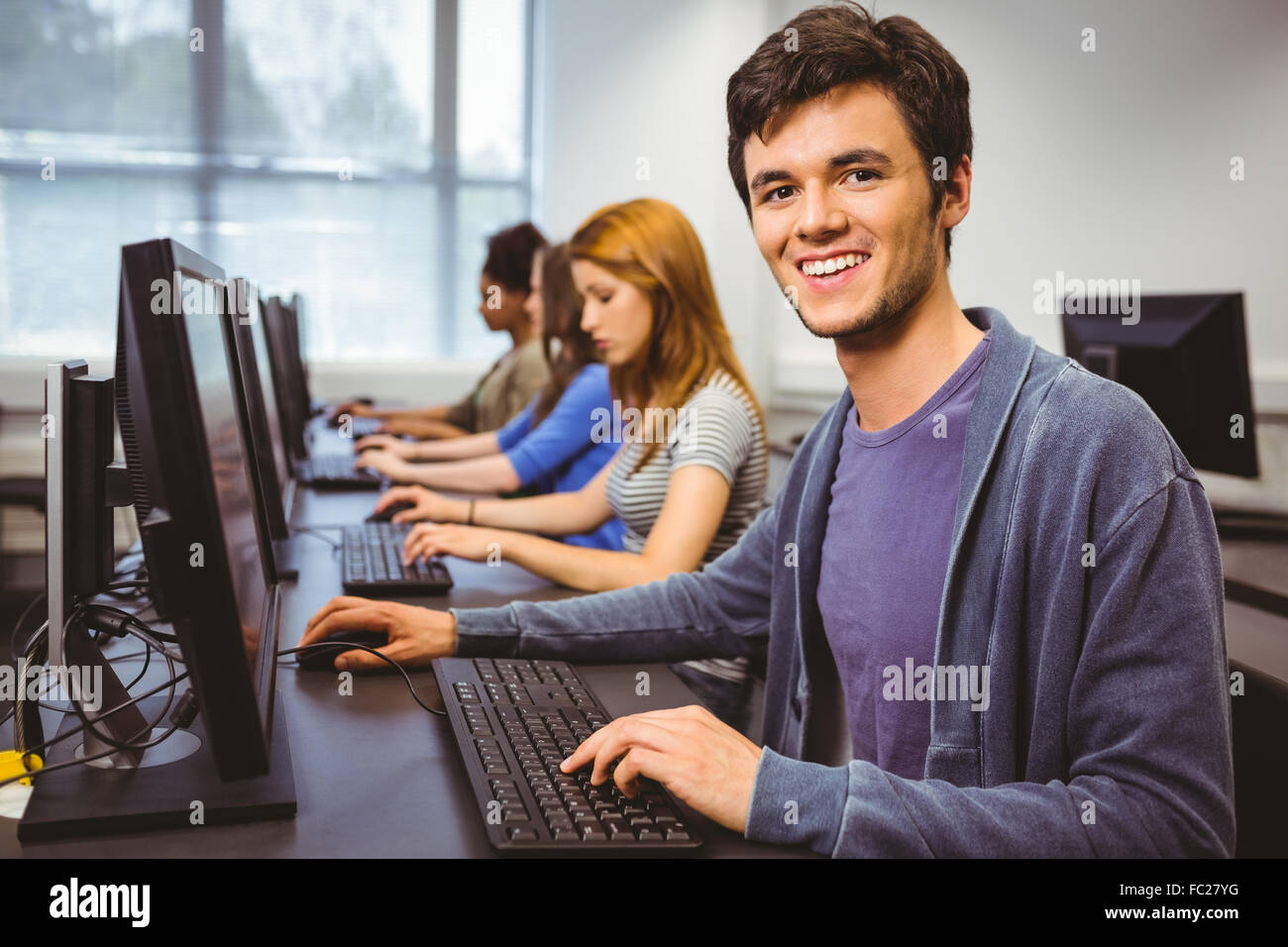 Happy student in computer class smiling at camera Stock Photo - Alamy