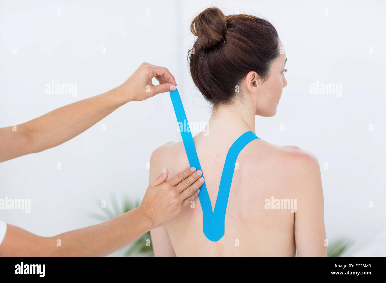 Physiotherapist applying blue kinesio tape to patients back Stock Photo ...