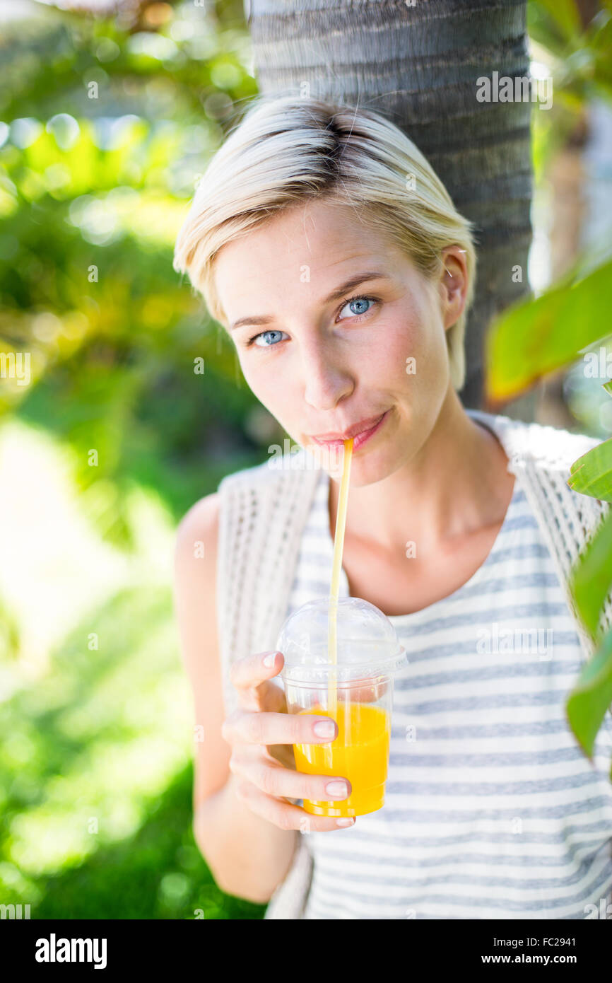 Pretty blonde woman smiling at the camera and drinking orange juice ...