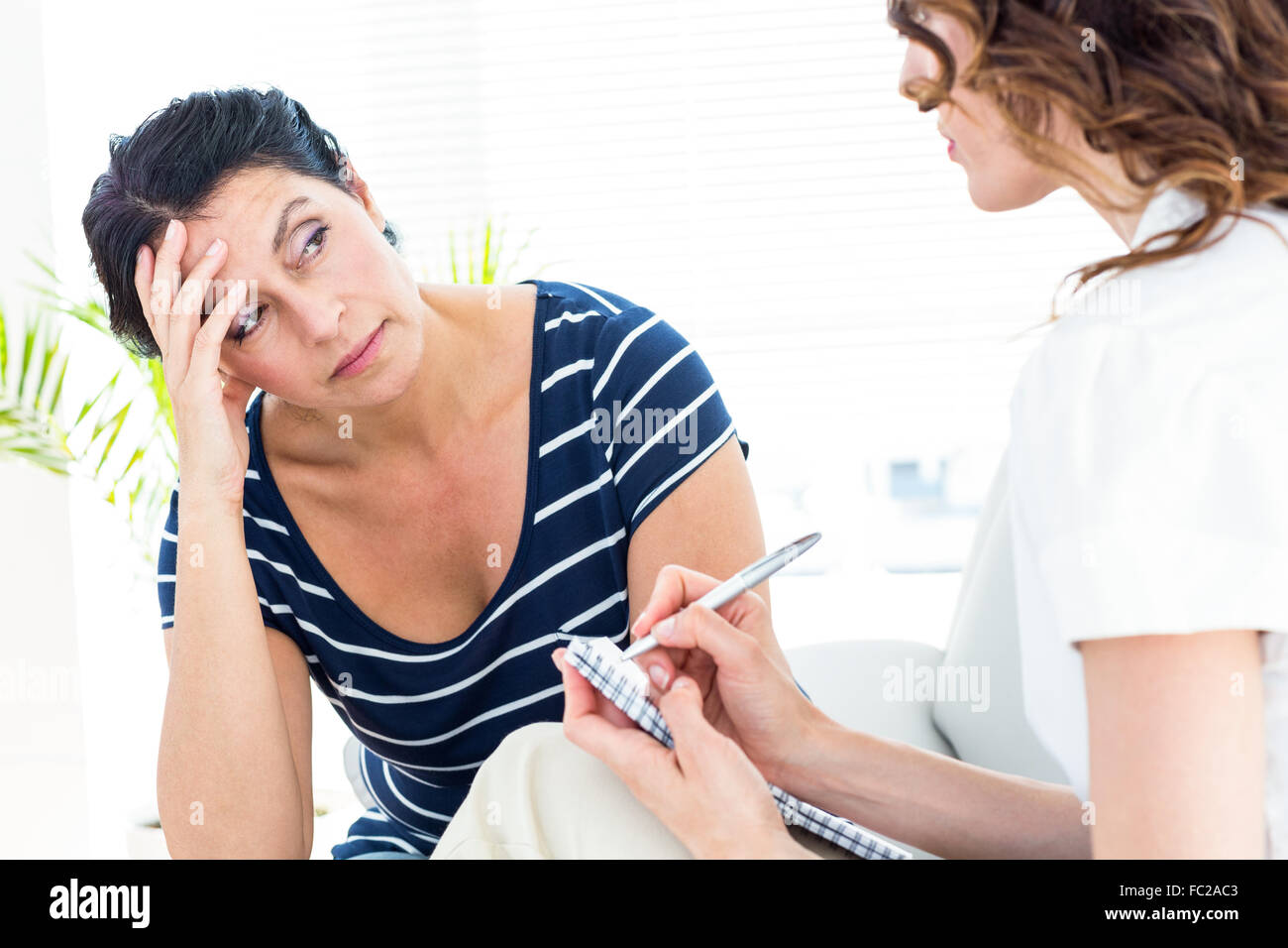 Therapist listening her patient and taking notes Stock Photo - Alamy
