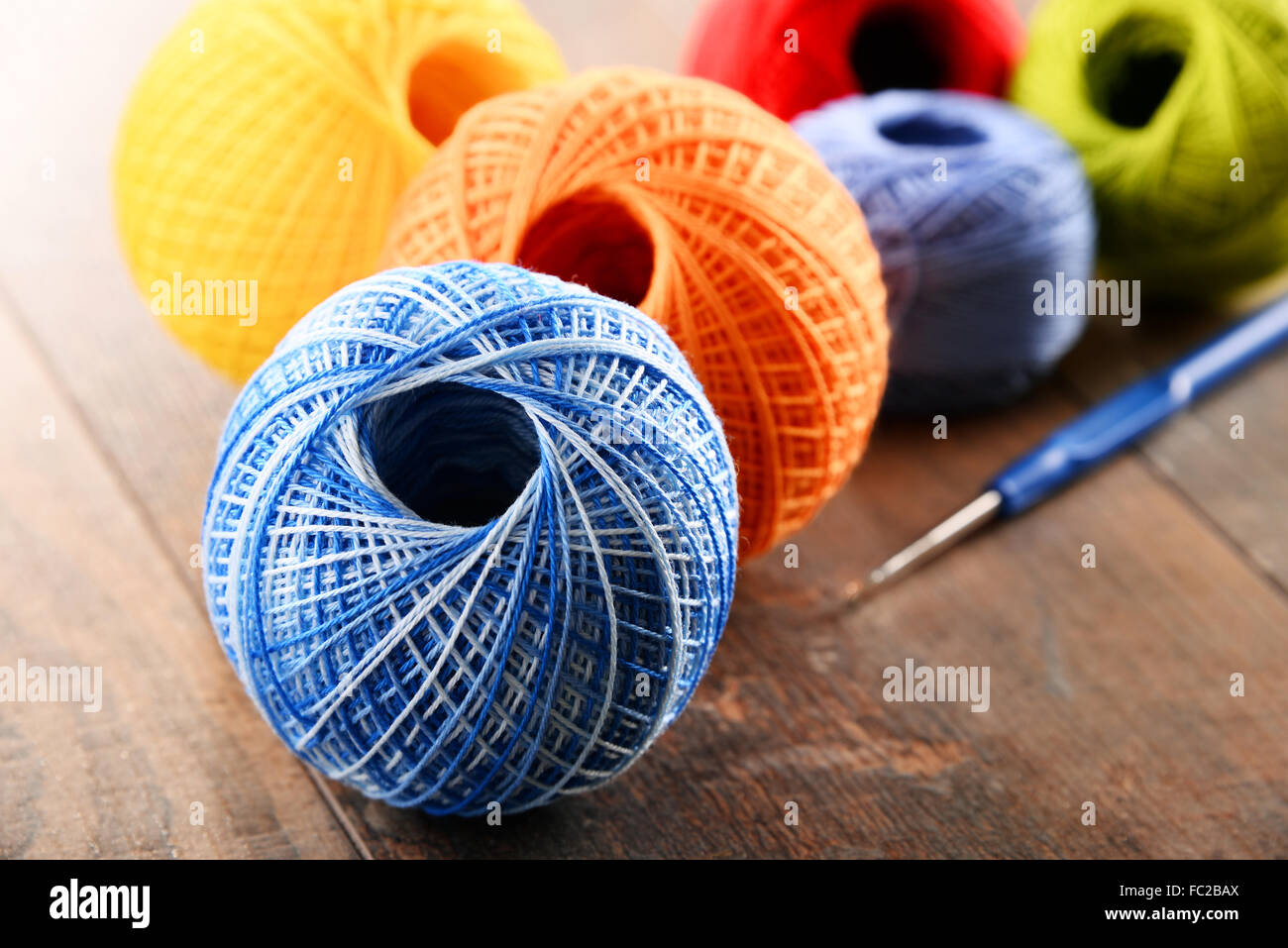 Colorful yarn for crocheting and hook on wooden table Stock Photo - Alamy