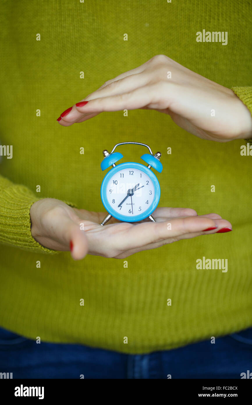 Little blue alarm clock in the hands of woman, the concept of saving ...