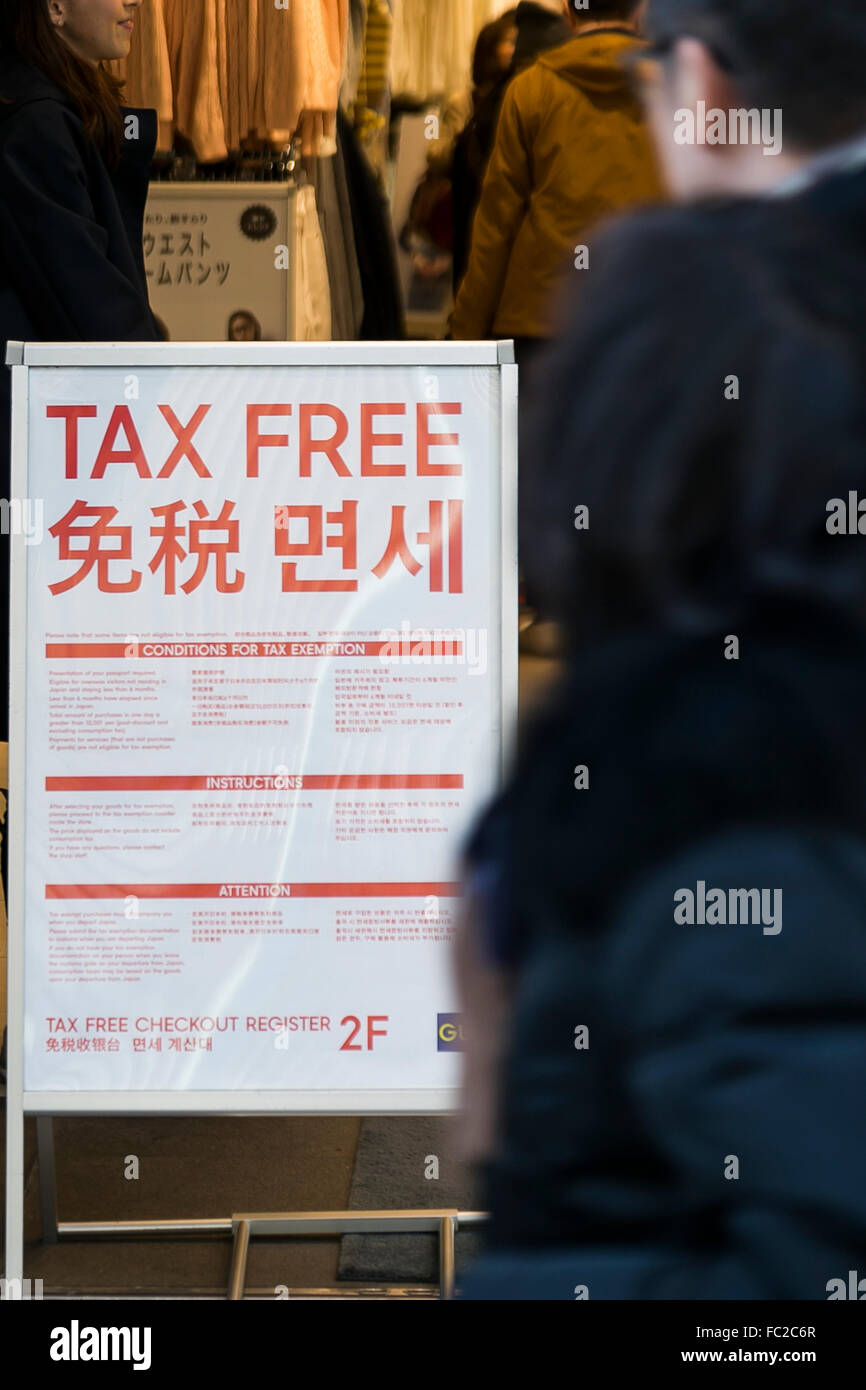 Foreign visitors walk past a Tax Free signboard on display at the ...