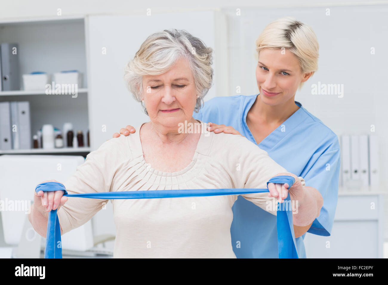 Nurse assisting senior woman in exercising with resistance band Stock ...