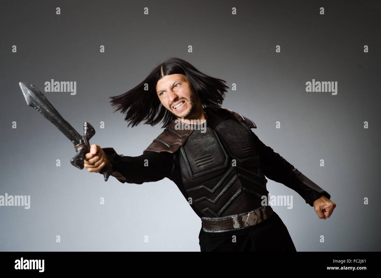 Angry knight with sword against dark background Stock Photo - Alamy