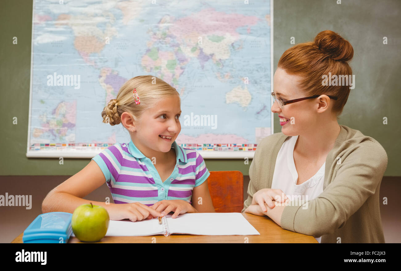 Teacher assisting girl with homework in classroom Stock Photo - Alamy