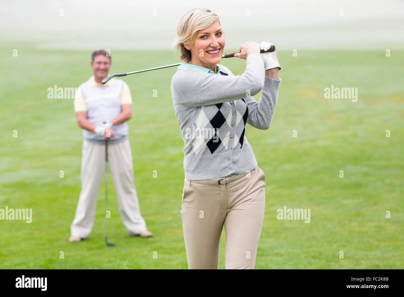 Lady golfer teeing off for the day watched by partner Stock Photo - Alamy