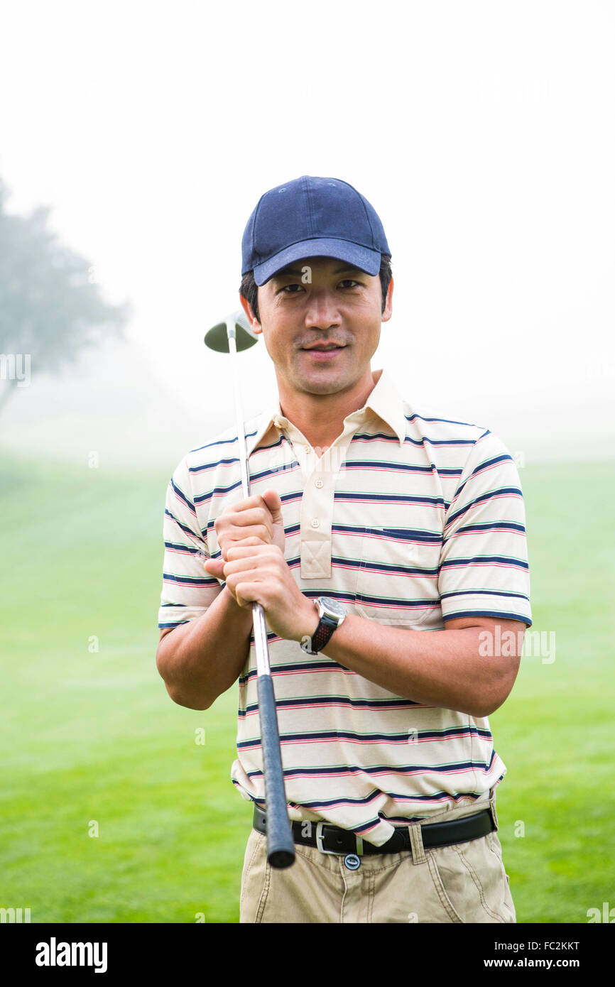 Golfer standing and holding his club smiling at camera Stock Photo - Alamy