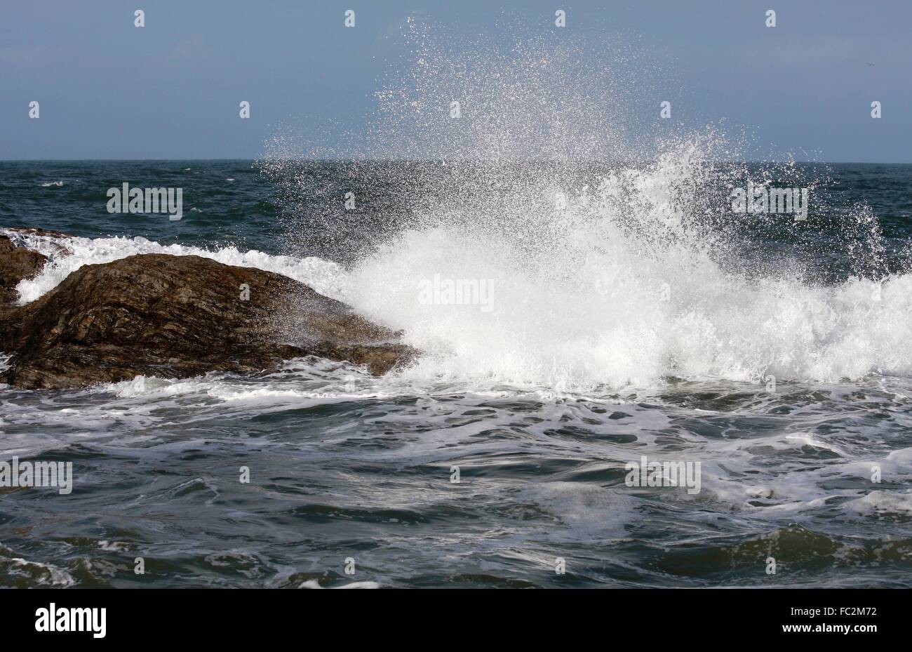 Ocean wave splashing over rock Stock Photo - Alamy