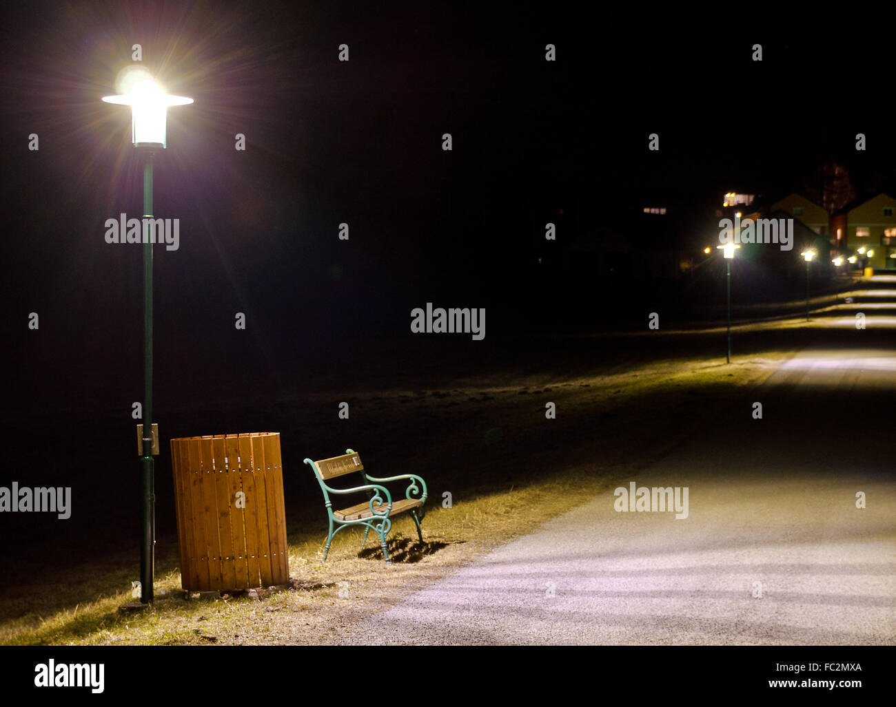 park bench and trash container at night Stock Photo - Alamy
