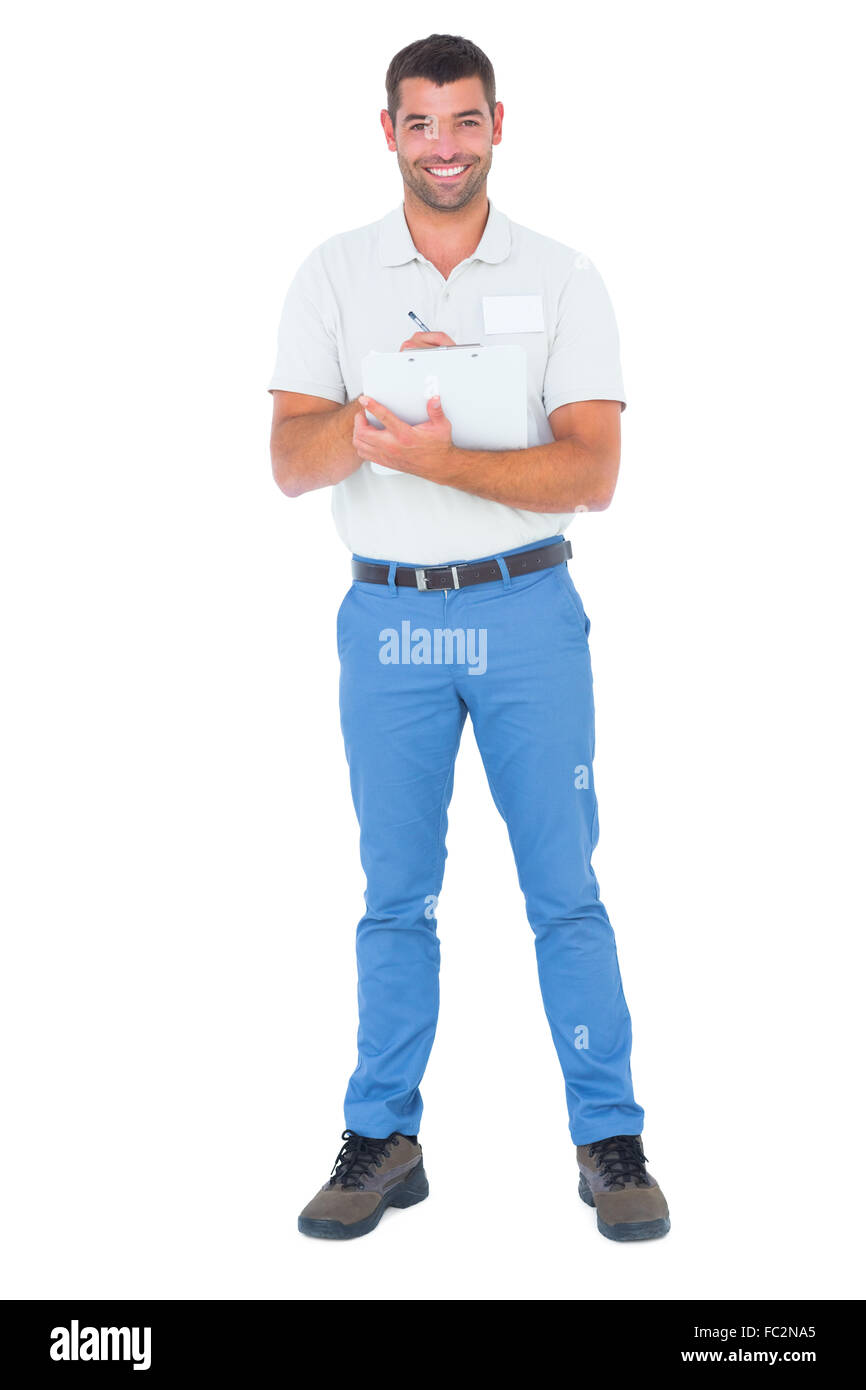 Confident male supervisor writing on clipboard over white background ...