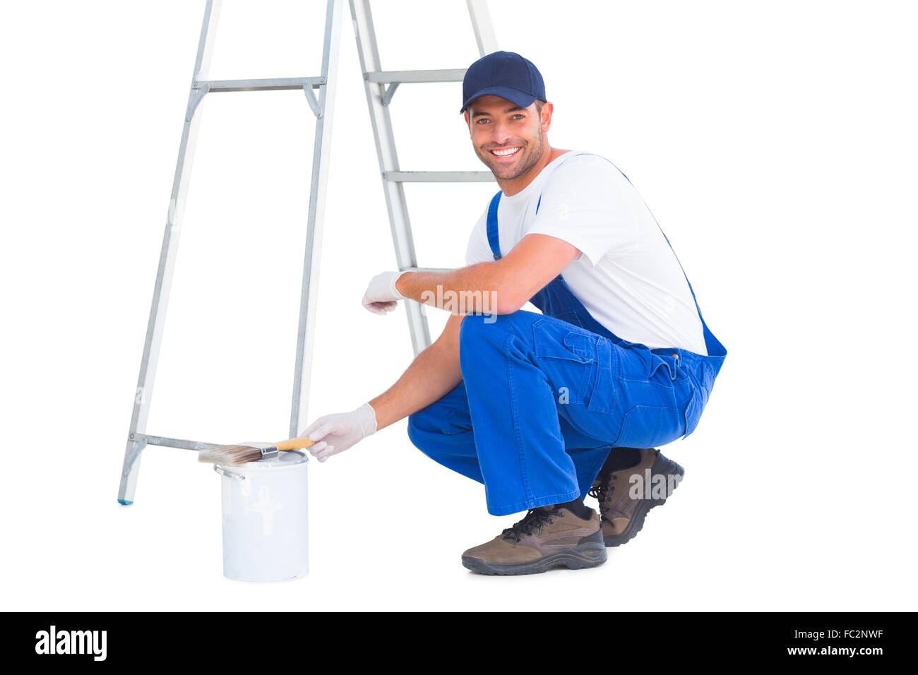 Portrait of happy handyman crouching by paint can Stock Photo - Alamy