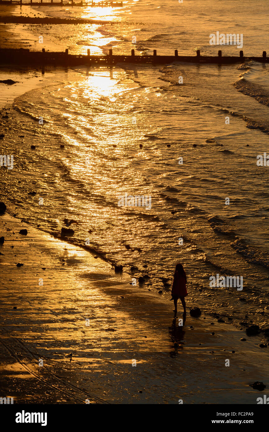 Person walking along the beach during sunset over Cromer Norfolk ...